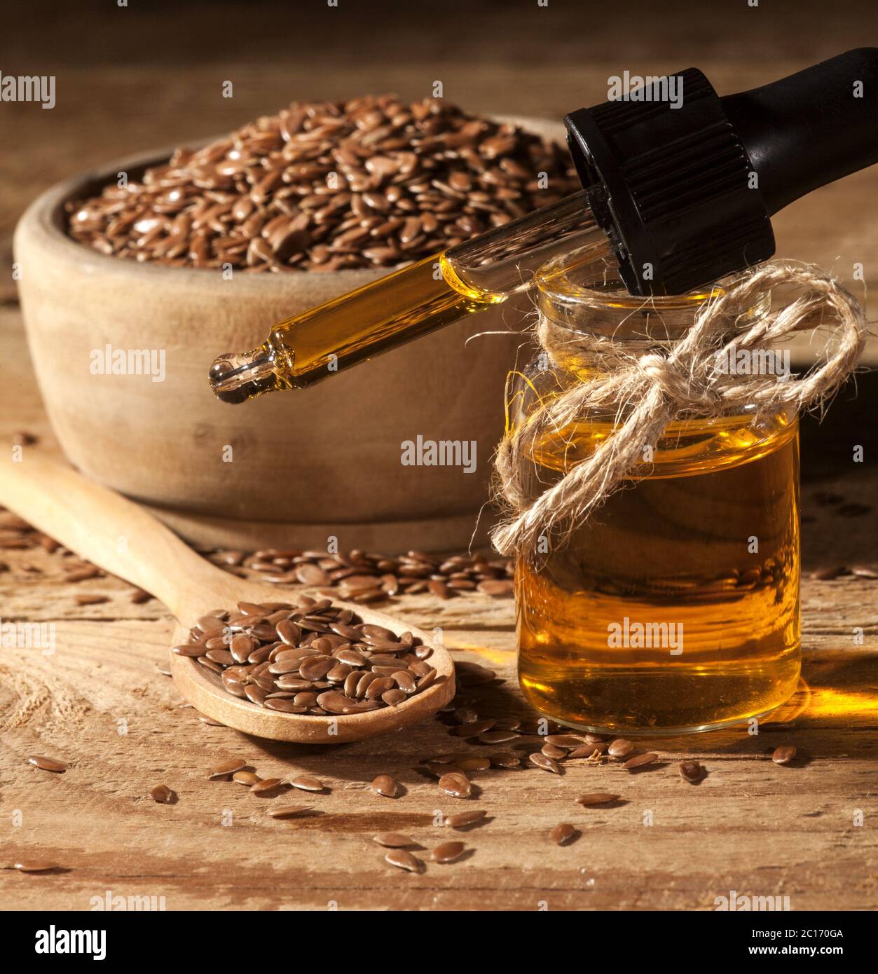 Linseed oil, spoon and bowl of linseeds on wooden background Stock Photo - Alamy