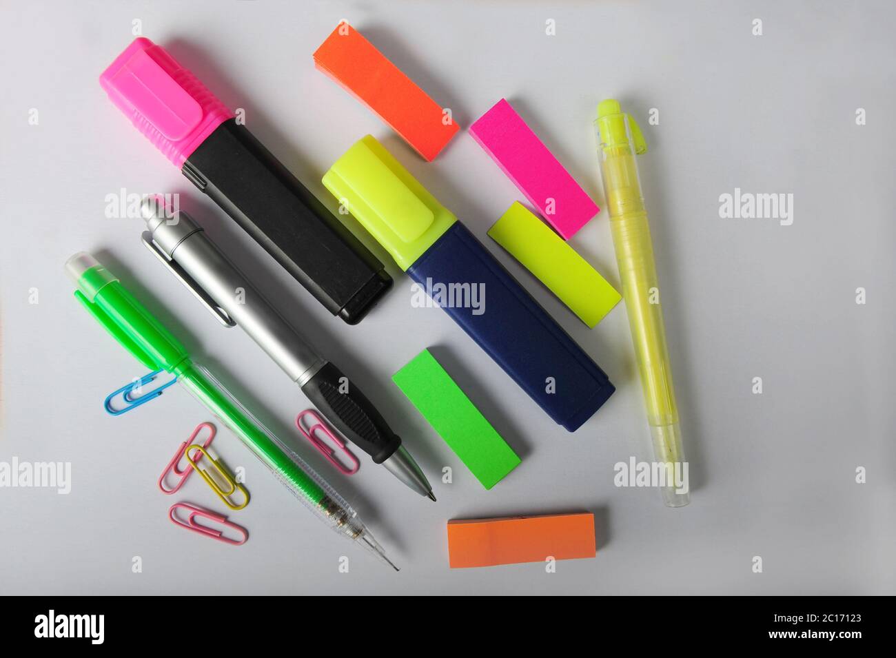 Colorful markers, pens, paper clips and post-it tabs shot from above on ...