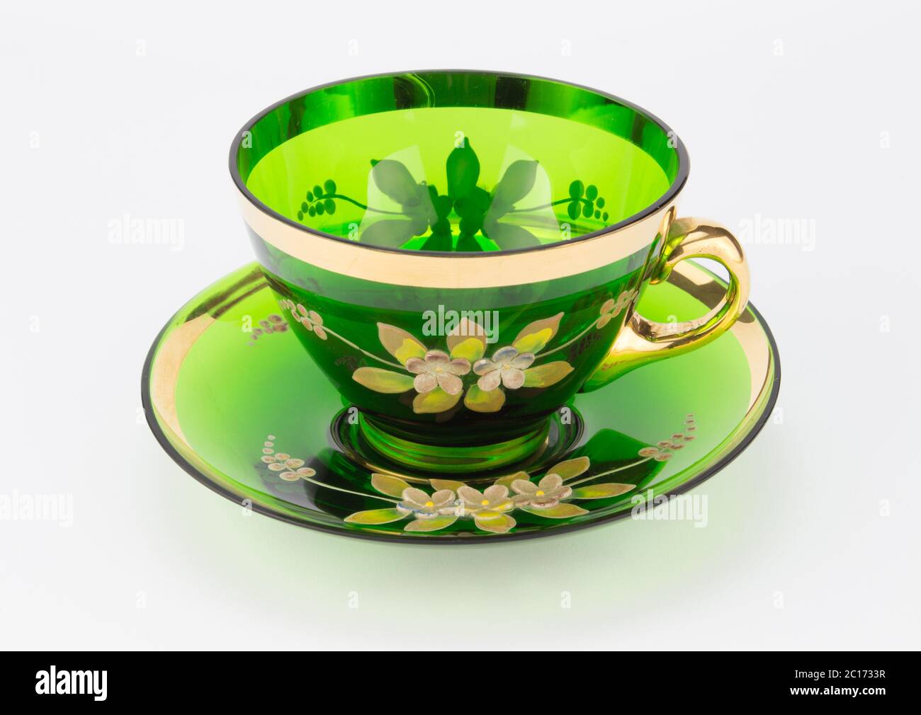 Antique transparent green glass teacup and saucer isolated on white ...