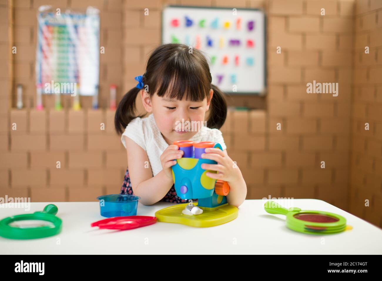 toddler girl play microscope for homeschooling Stock Photo - Alamy