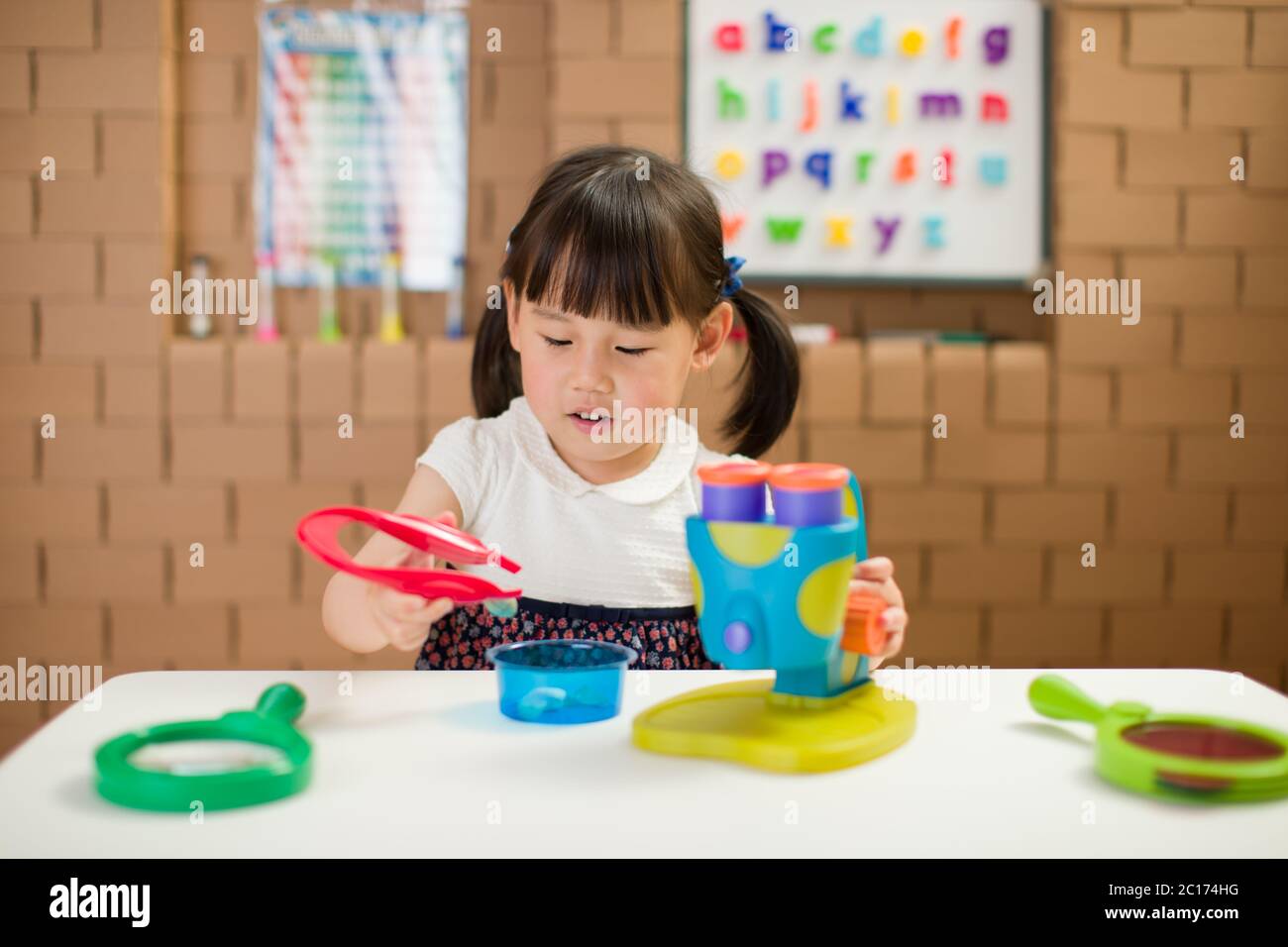 toddler girl play microscope for homeschooling Stock Photo - Alamy