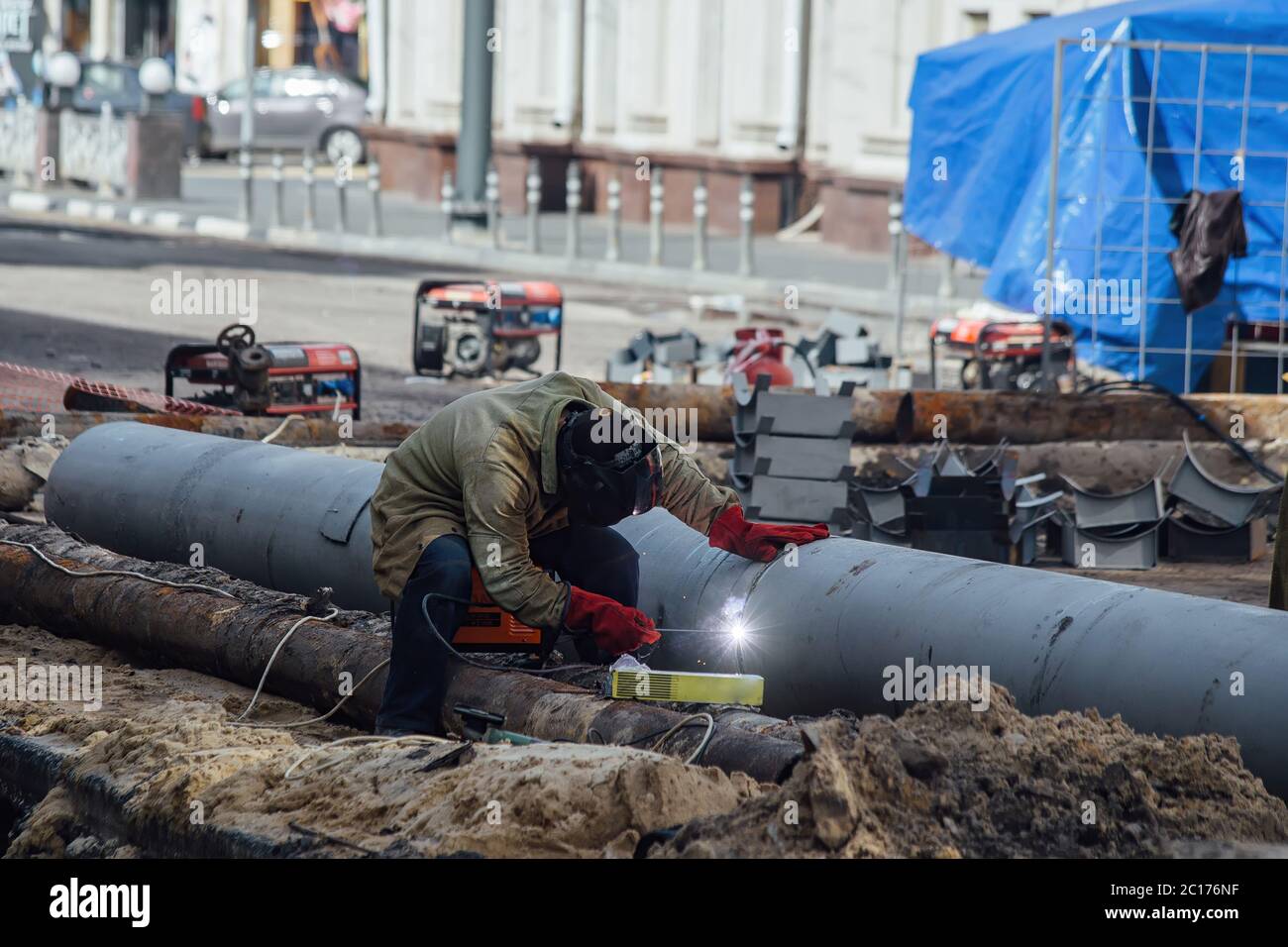 Repairing of city water supply or sewer pipeline. Worker is welding ...