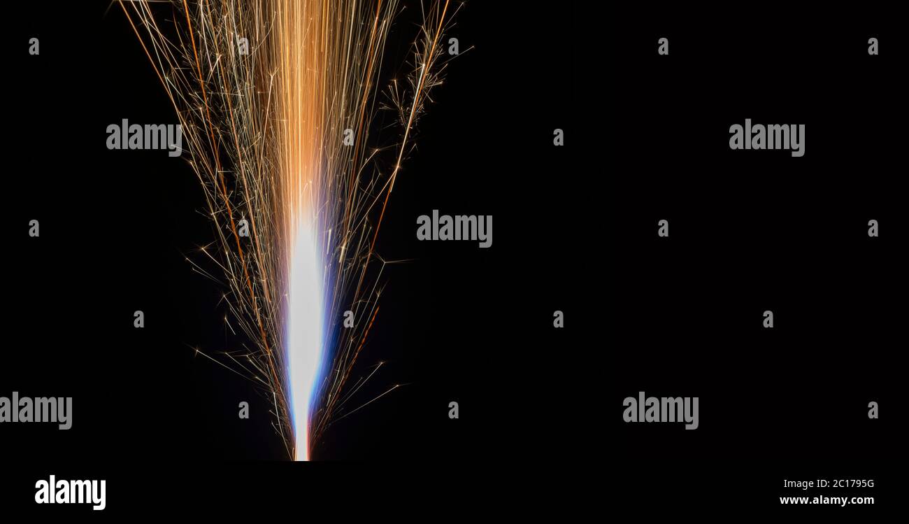 Shot of yellow gunpowder sparks shooting upwards on black background ...