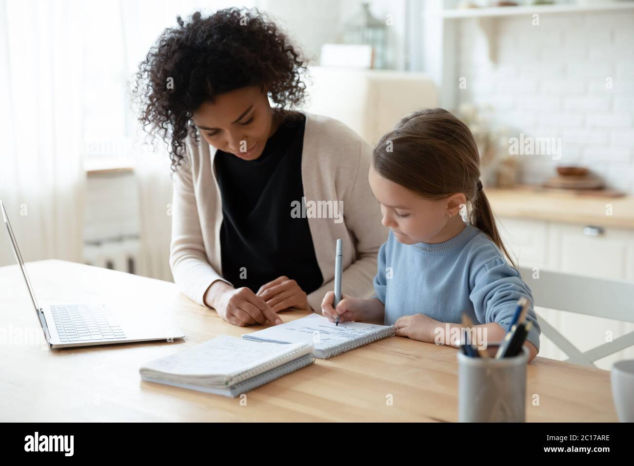African tutor helps with school subject to little kid girl Stock Photo ...