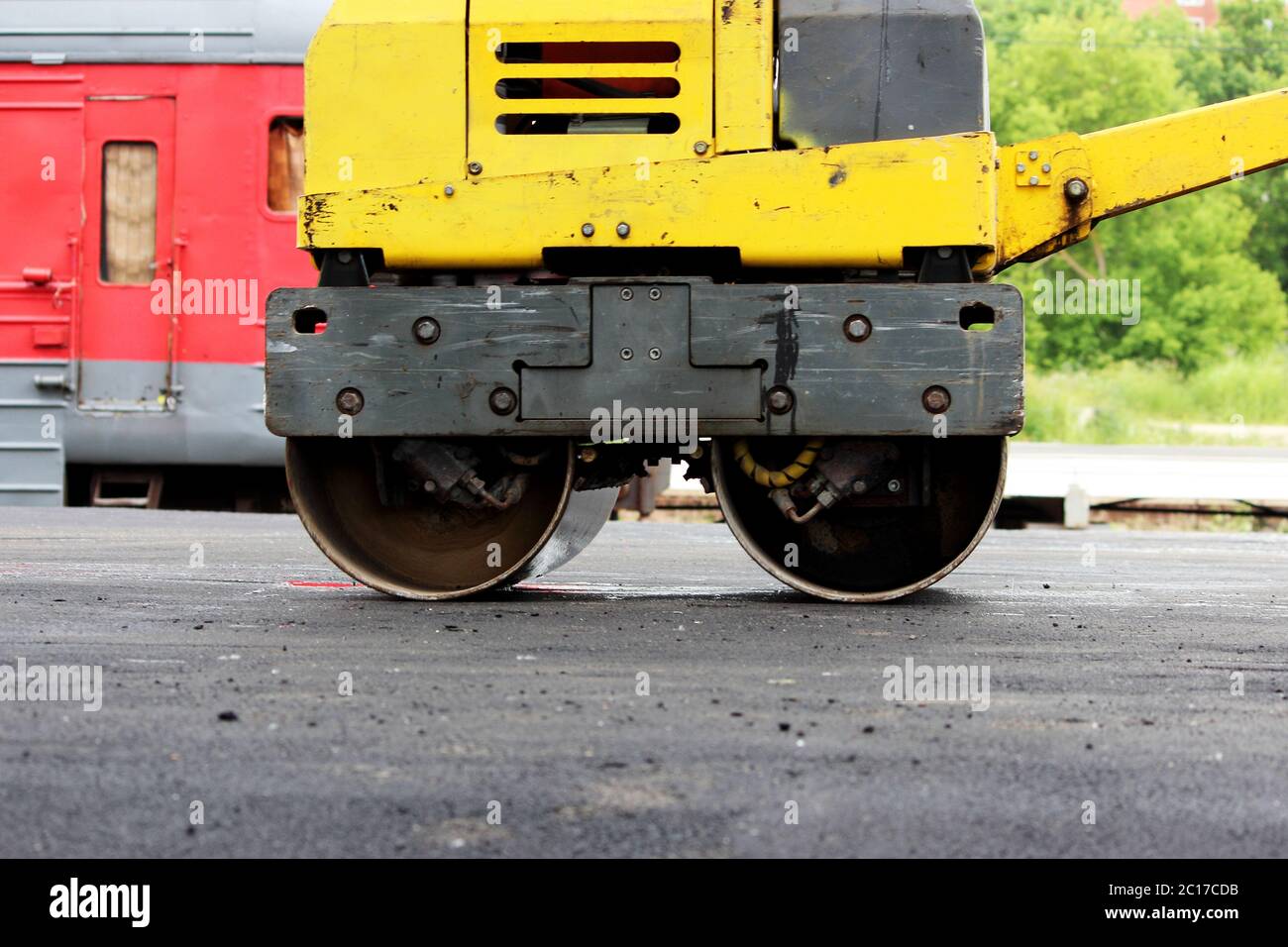 A small compactor covers with asphalt to platform at the railway ...