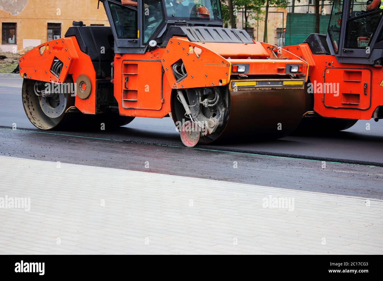 Two heavy compactor tires the upper layer of asphalt in the ...