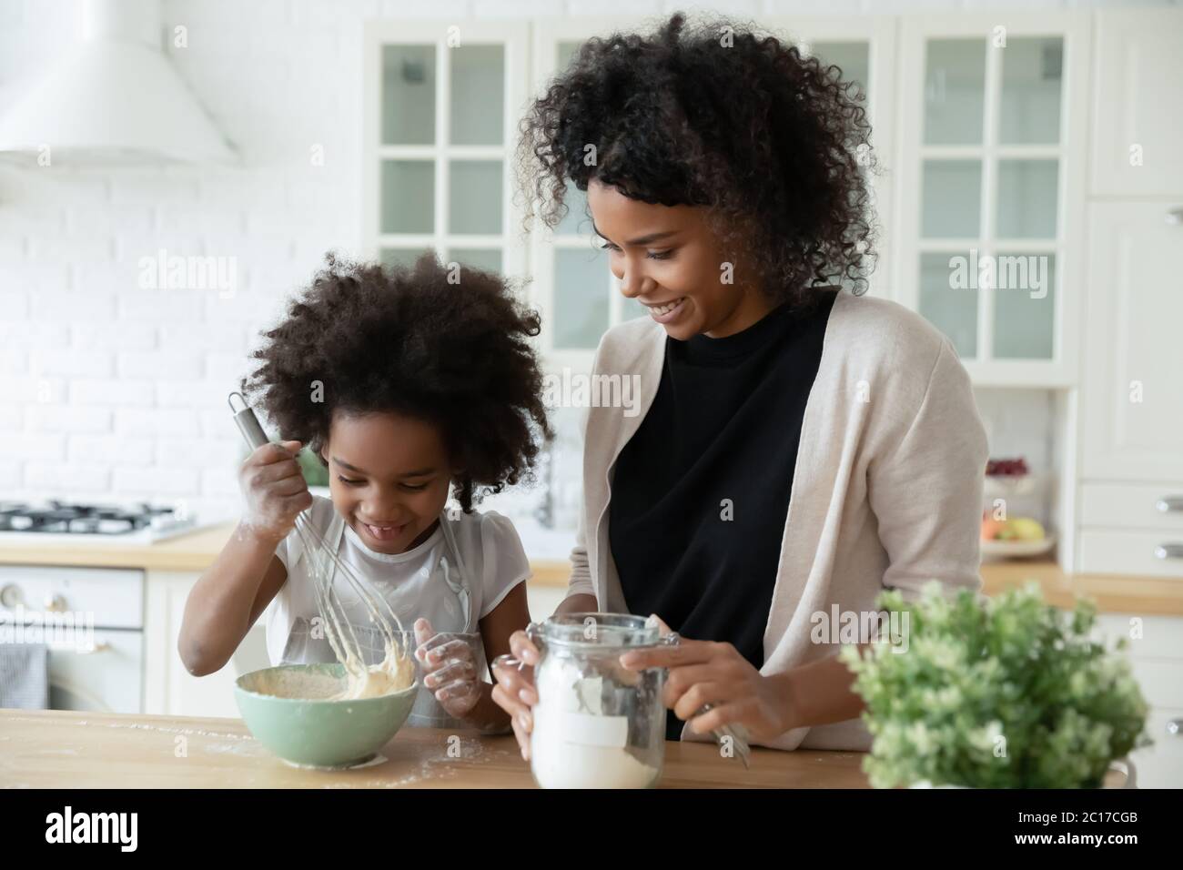 Little daughter and African mother cooking together in kitchen Stock ...