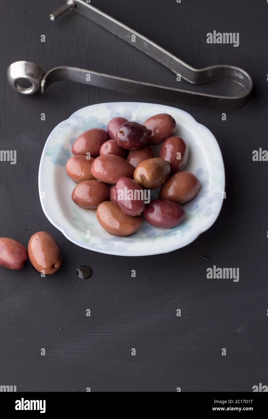 Purple olives in small white bowl with two on black chalk board texture ...