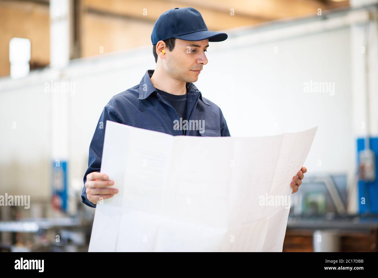 Blue dressed engineer reading a bluepring drawing in an industrial ...