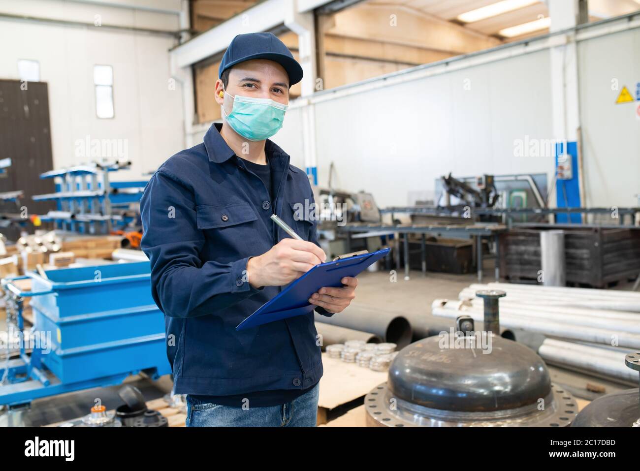Industrial worker writing on a document in a factory Stock Photo - Alamy