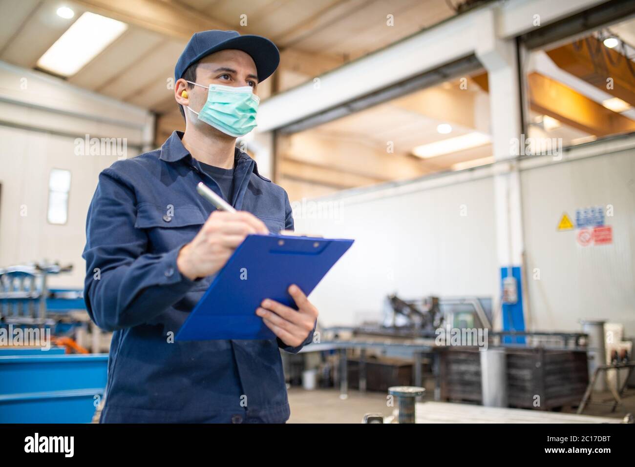 Industrial worker writing on a document in a factory Stock Photo - Alamy