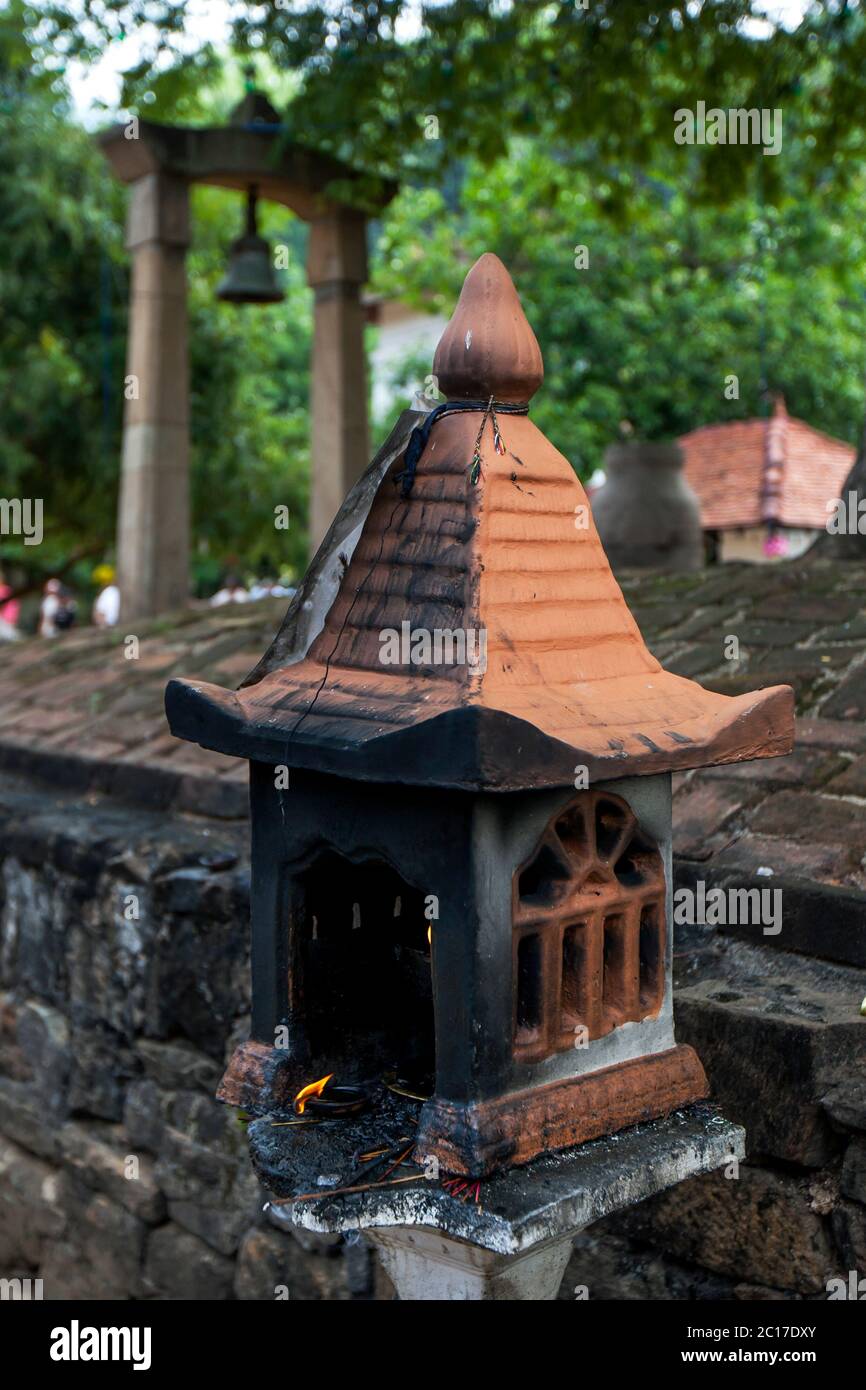 A small Buddhist shrine with a lit oil lamp sitting under a tree at the ...