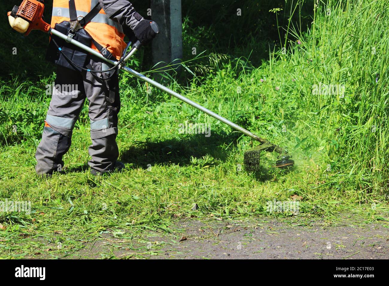 Worker mowing grass with a trimming machine Stock Photo - Alamy