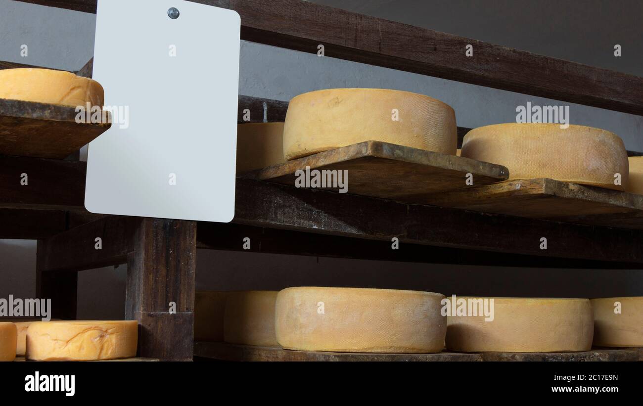 Approach to a cheese on wooden shelves inside a cheese aging cellar ...