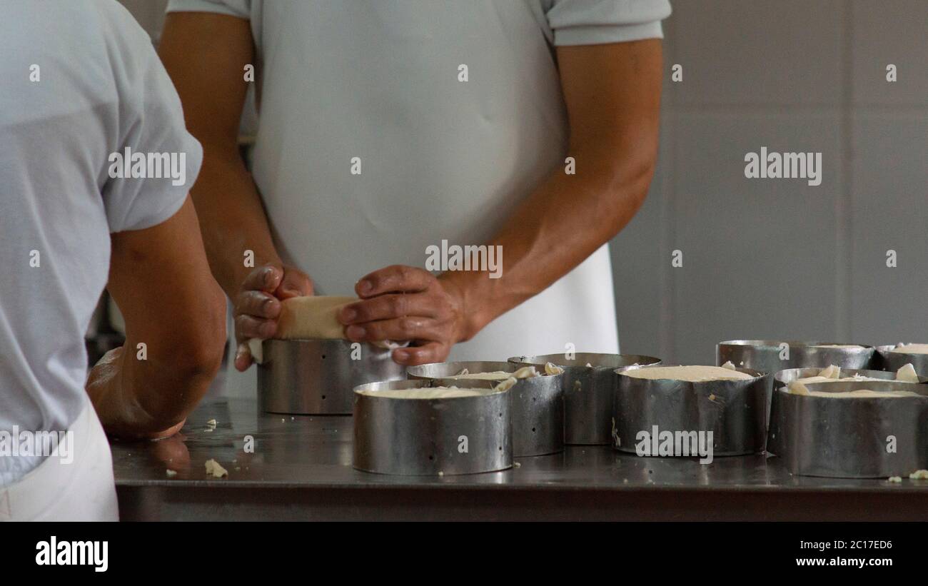 Approach of a worker placing the raw cheese in metal molds. Cheese ...