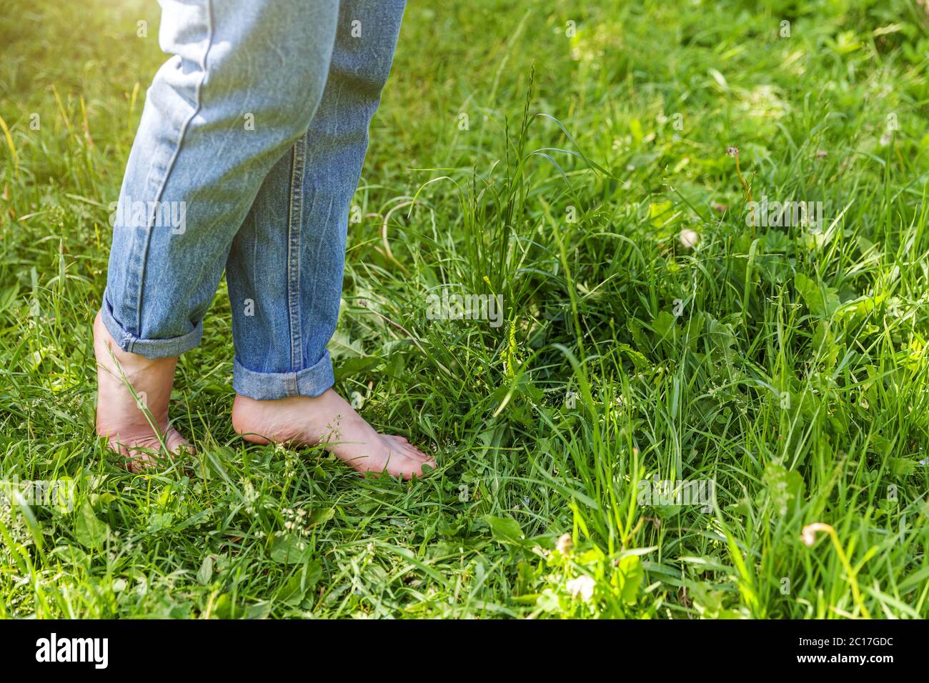 Two beautiful female feet walking on grass in sunny summer morning ...