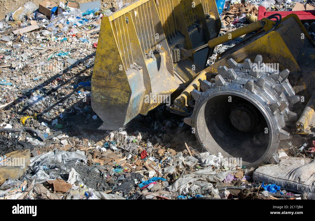 Close up of bulldozer working on the huge landfill or garbage dump pile ...