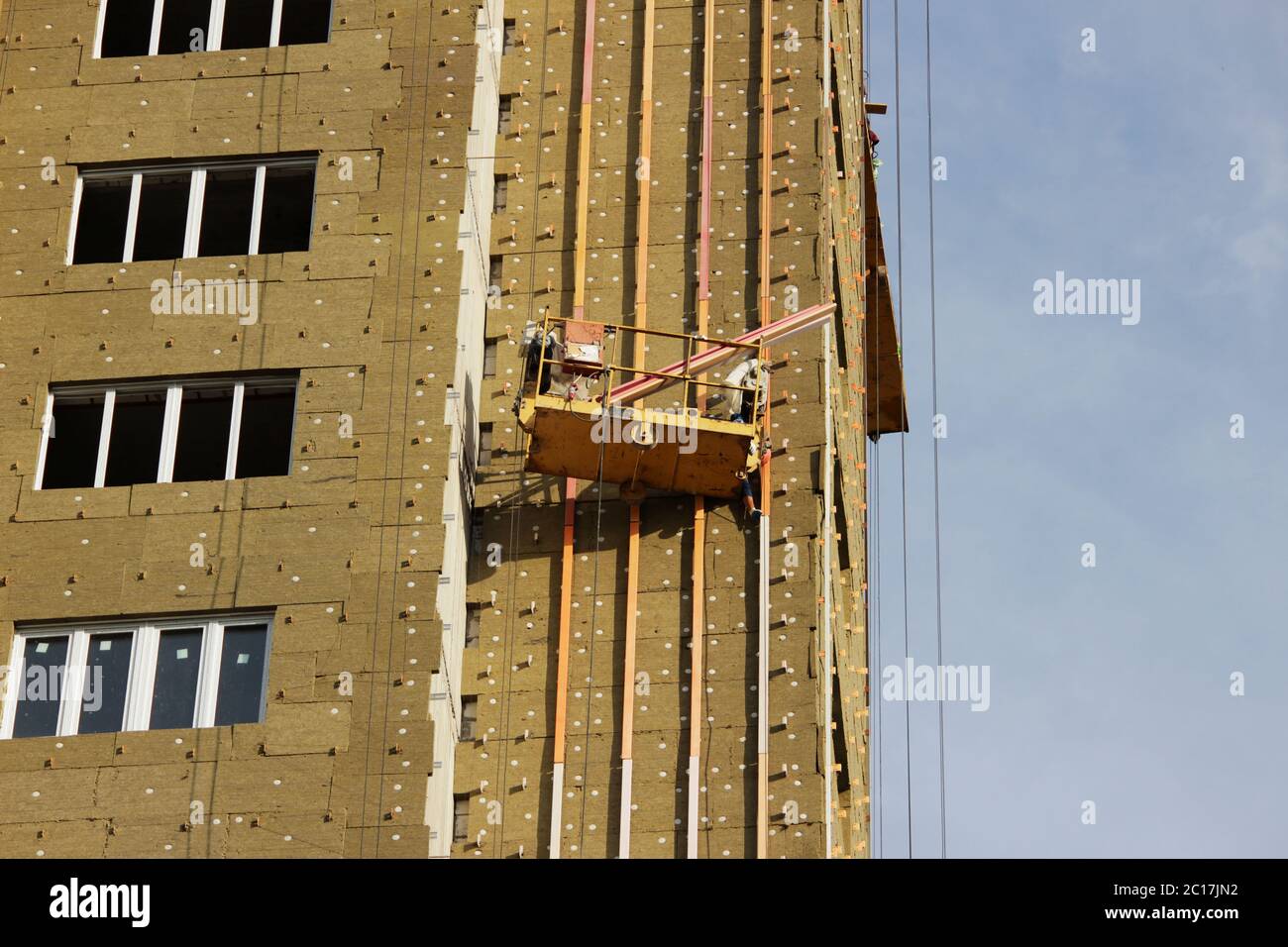 worker in yellow suspended cradle mounts environmental boards for ...