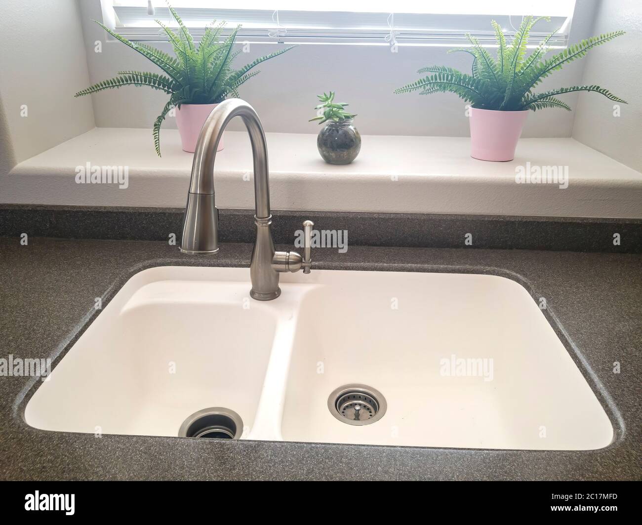 Sink with double bowl and stainless steel faucet against window of home ...