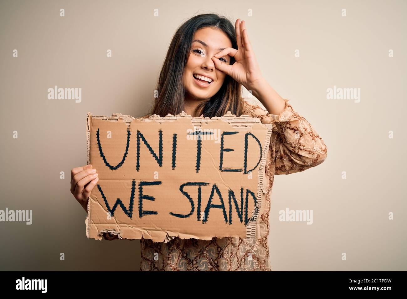 Young beautiful brunette woman asking for union holding banner with ...
