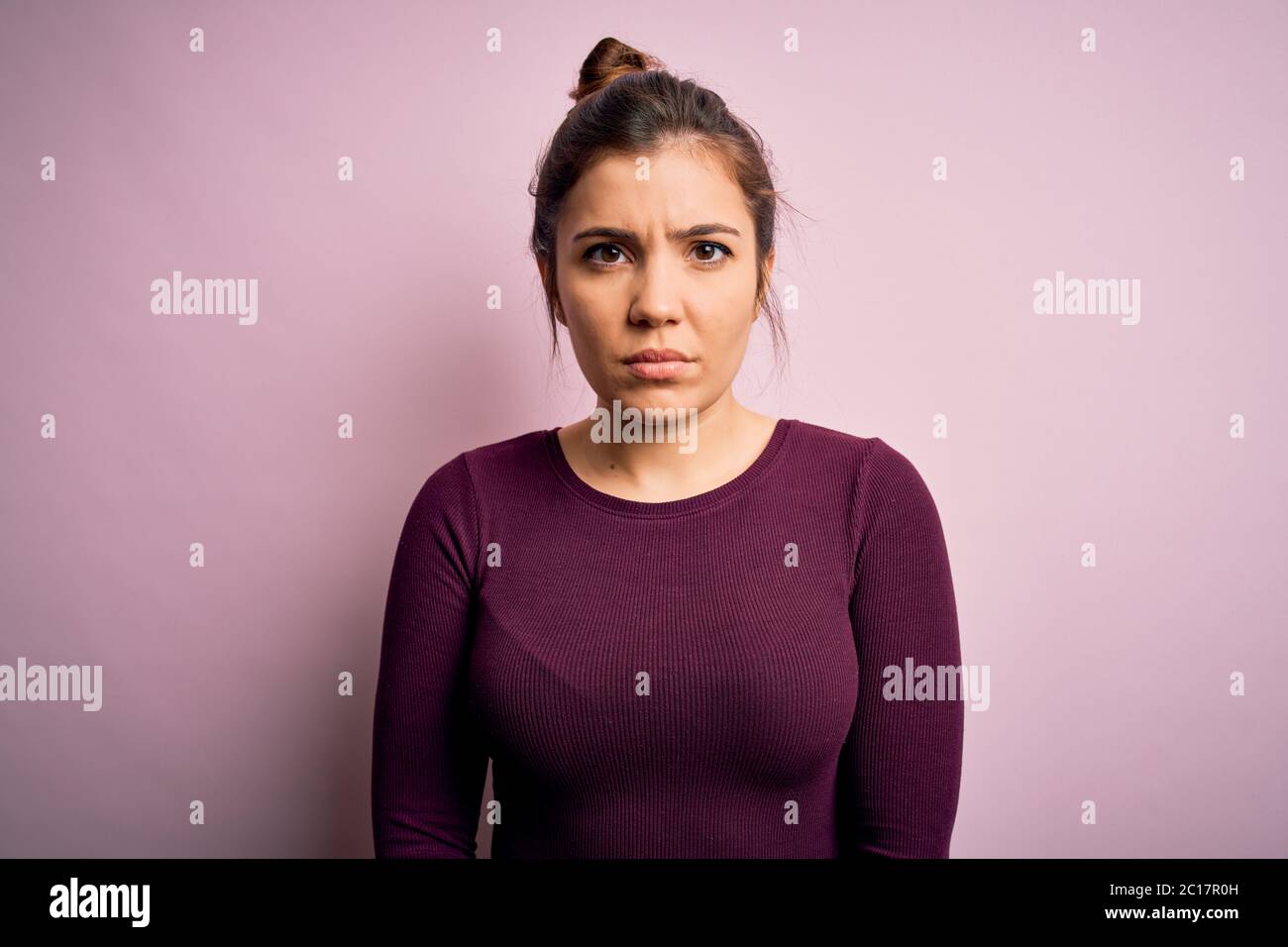 Beautiful young woman wearing casual bun hairstyle over pink isolated ...