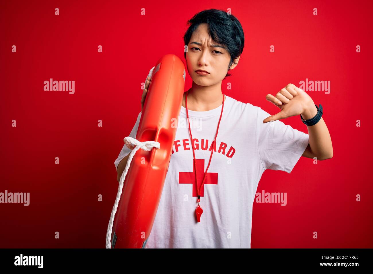 Young beautiful asian lifeguard girl using whistle holding orange float ...