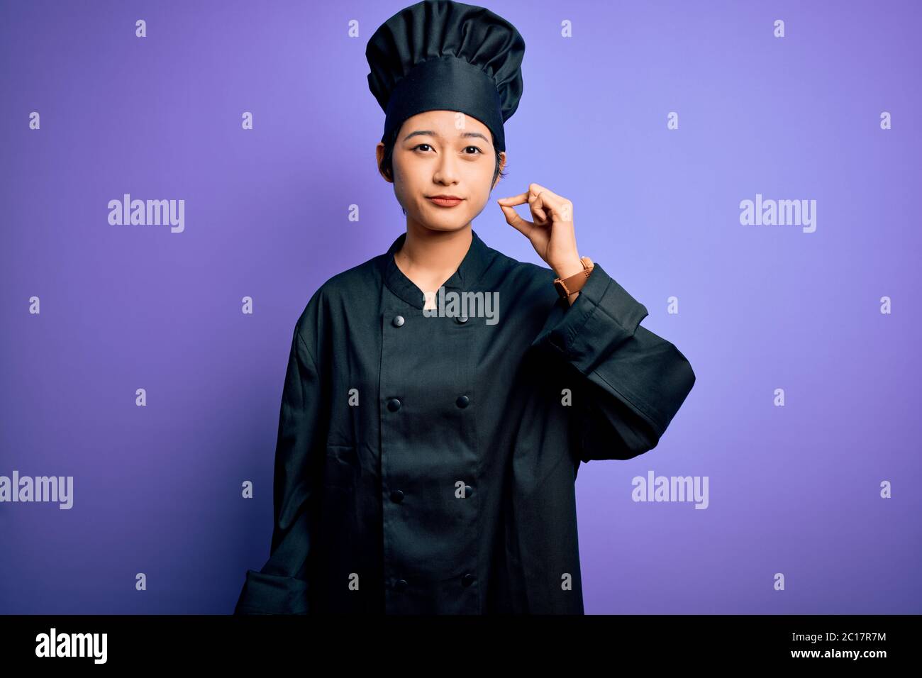 Young beautiful chinese chef woman wearing cooker uniform and hat over ...