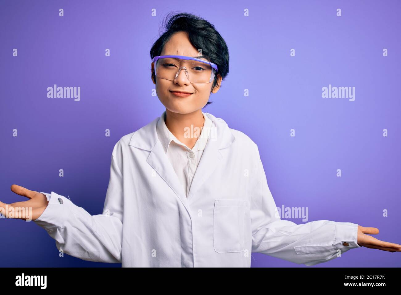 Young beautiful asian scientist girl wearing coat and glasses over ...