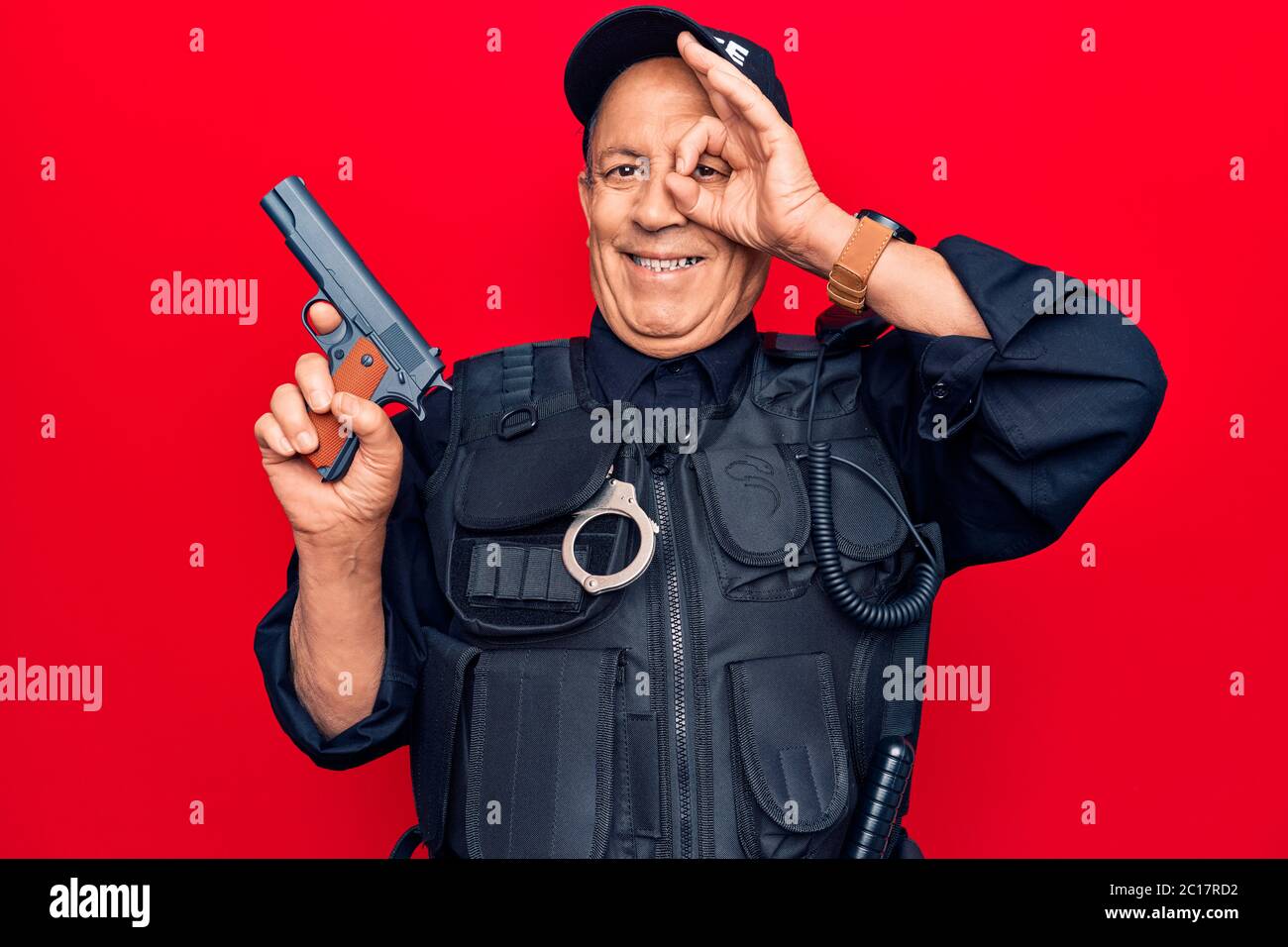 Senior man with grey hair wearing police uniform holding gun smiling ...