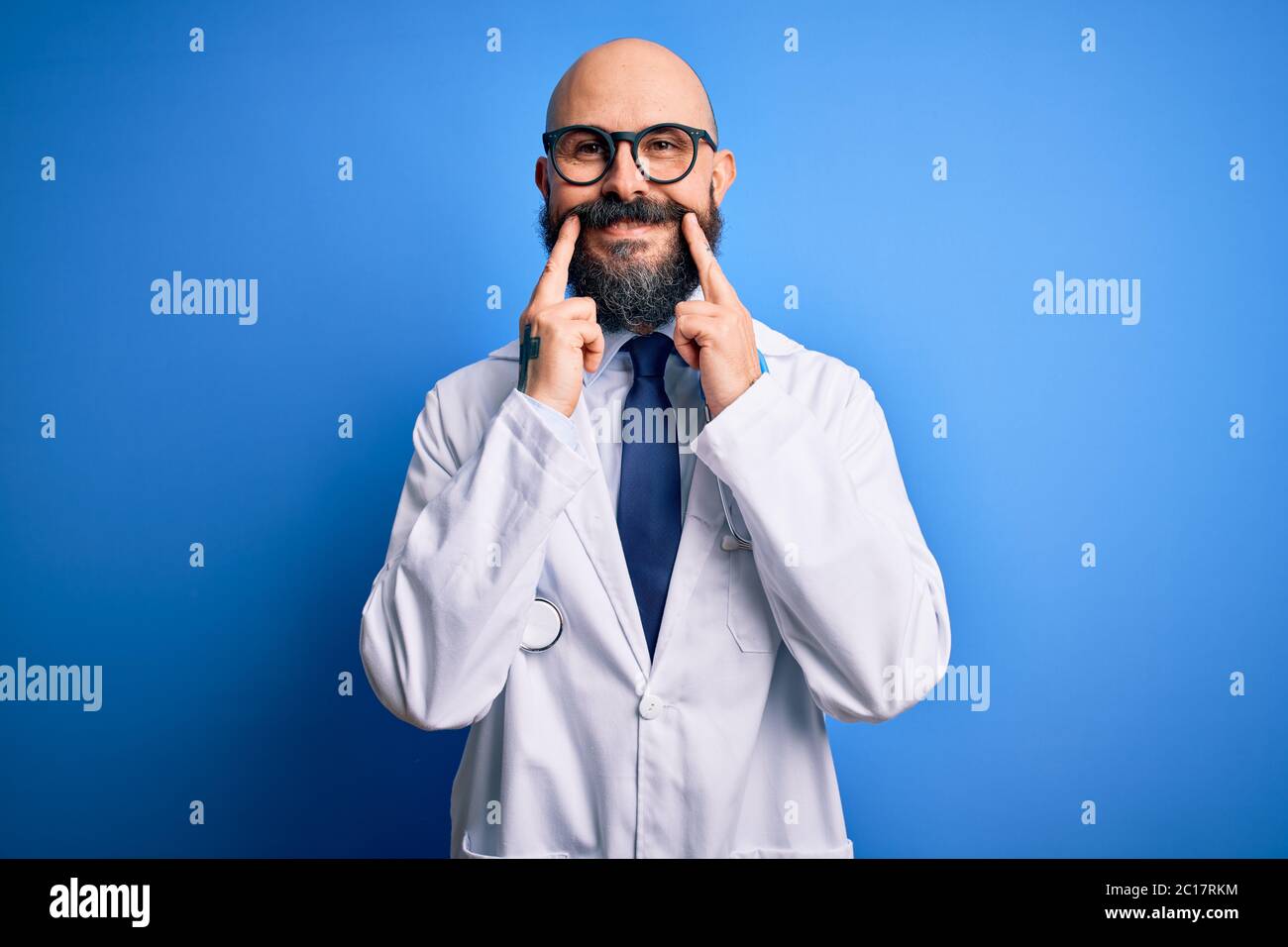 Handsome bald doctor man with beard wearing glasses and stethoscope ...
