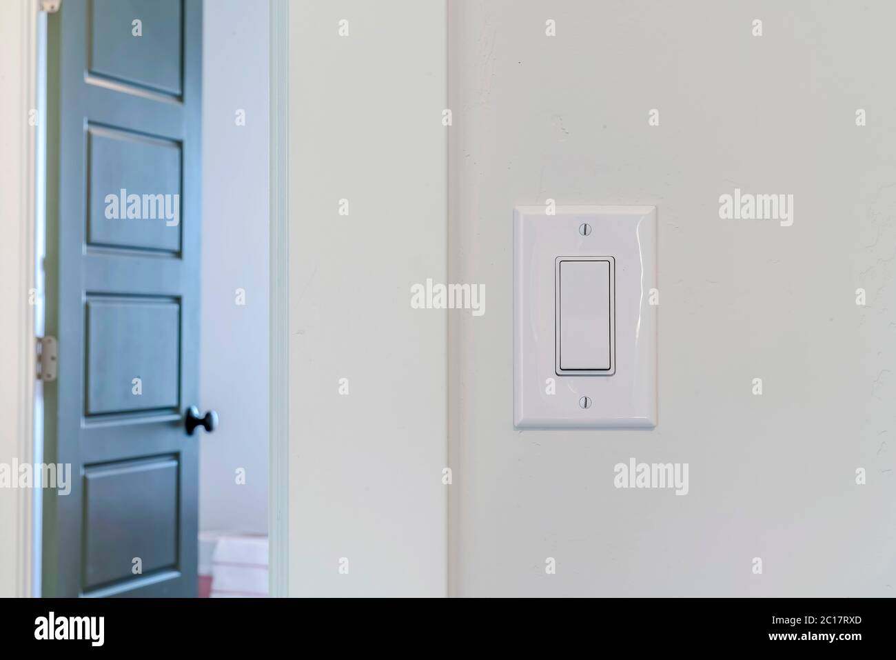 Electrical rocker light switch on white wall against blurry door ...