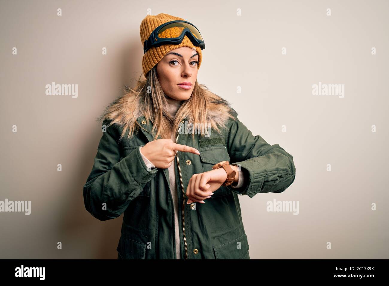 Young brunette skier woman wearing snow clothes and ski goggles over ...