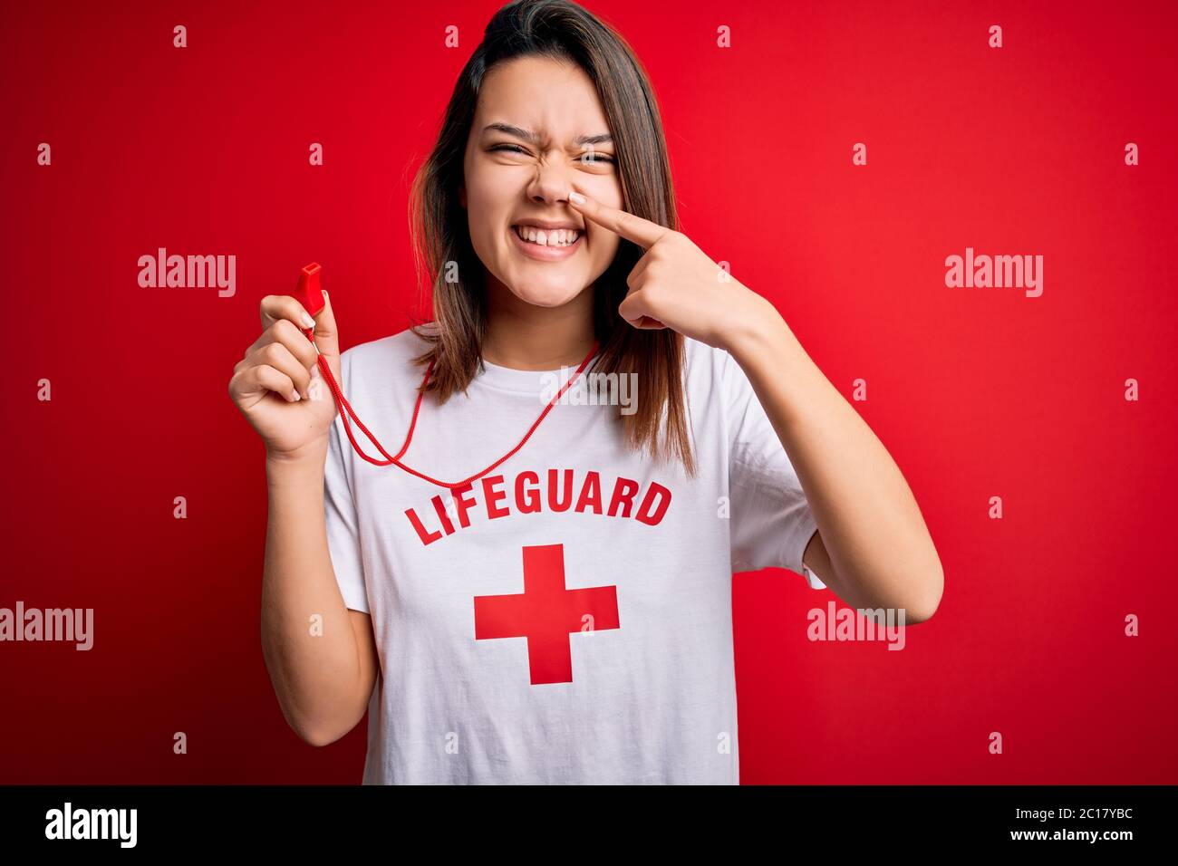 Young beautiful brunette lifeguard girl wearing t-shirt with red cross ...
