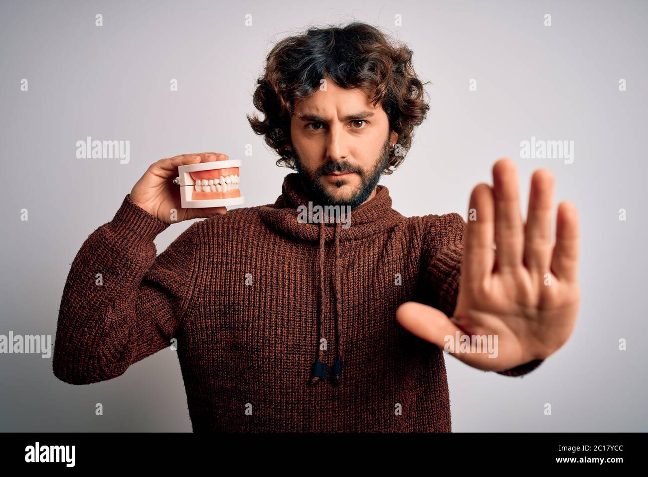 Young handsome man with beard holding plastic denture teeth over ...