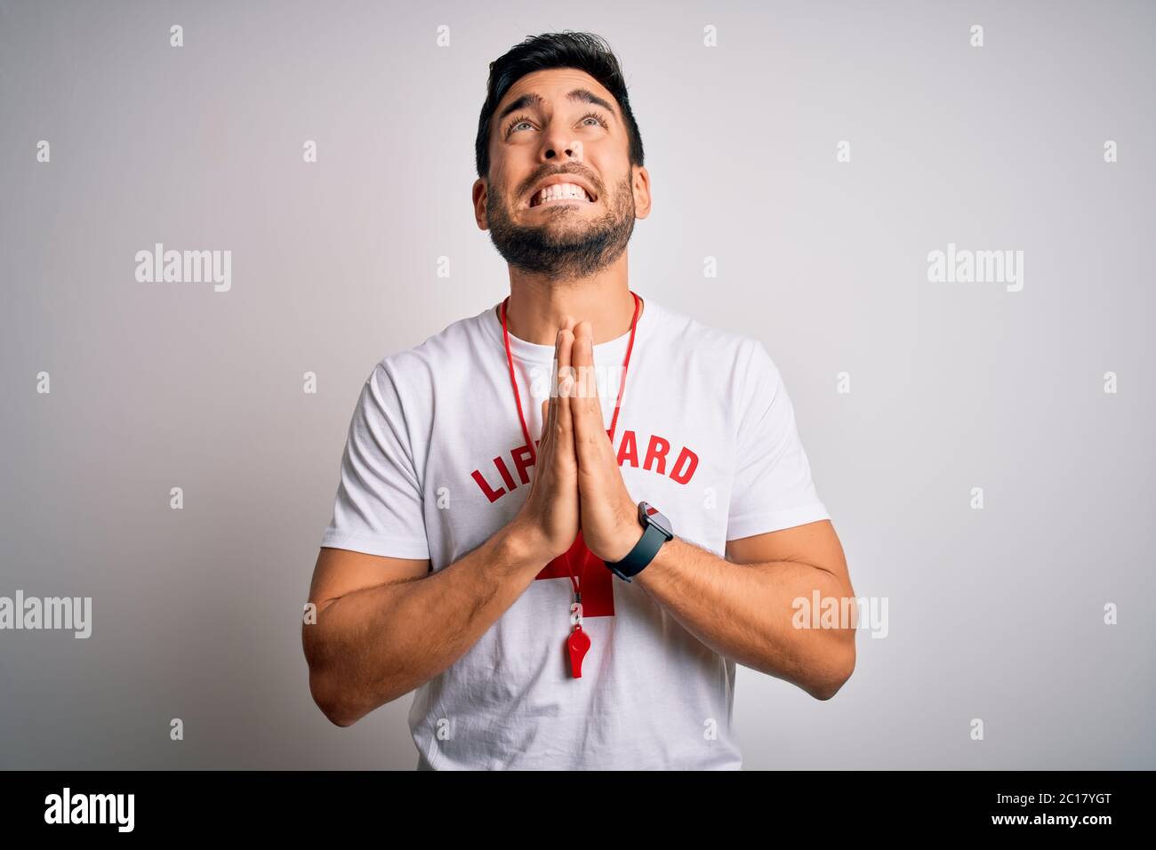 Young handsome lifeguard man with beard wearing t-shirt with red cross ...
