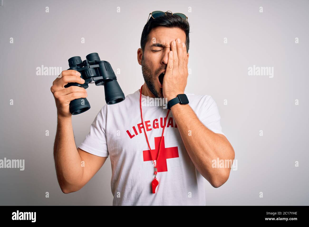 Young lifeguard man with beard wearing t-shirt with red cross and ...