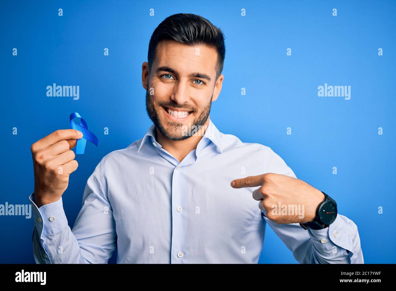 Young handsome man holding blue ribbon as prostate campaing support ...