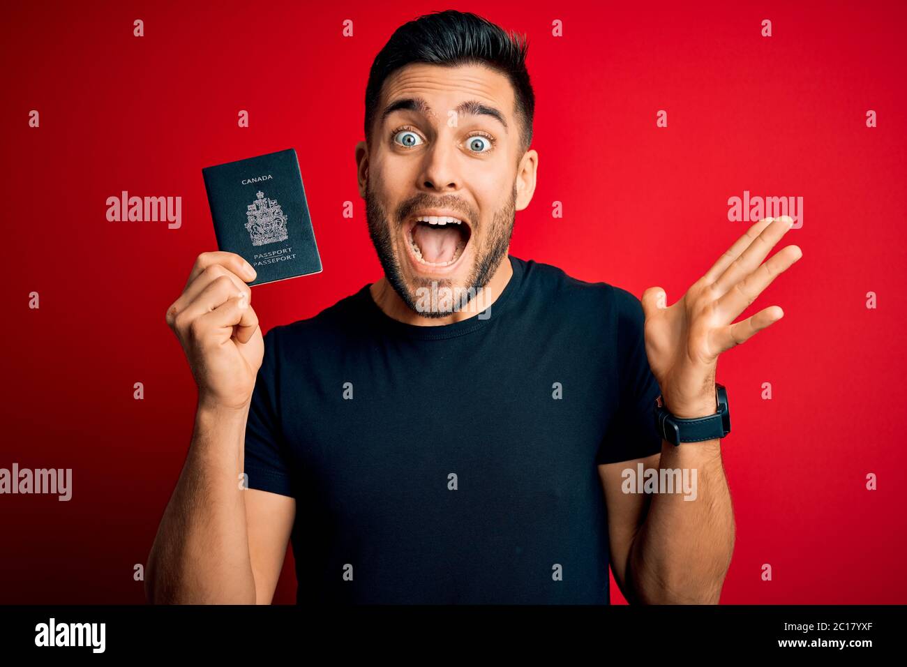 Young handsome tourist man holding canada canadian passport id over red ...