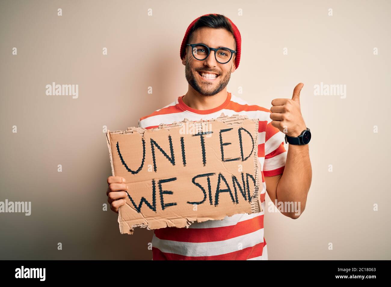 Handsome activist man protesting wearing glasses holding cardboard with ...