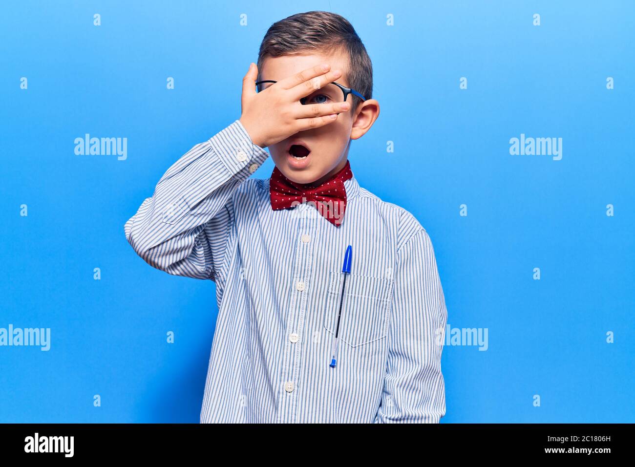 Cute blond kid wearing nerd bow tie and glasses peeking in shock ...