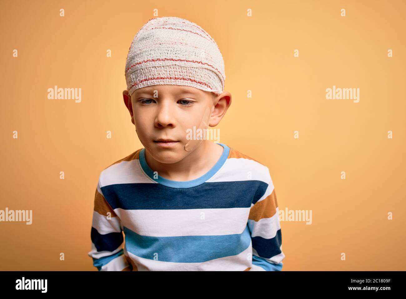 Young little caucasian kid injured wearing medical bandage on head over ...