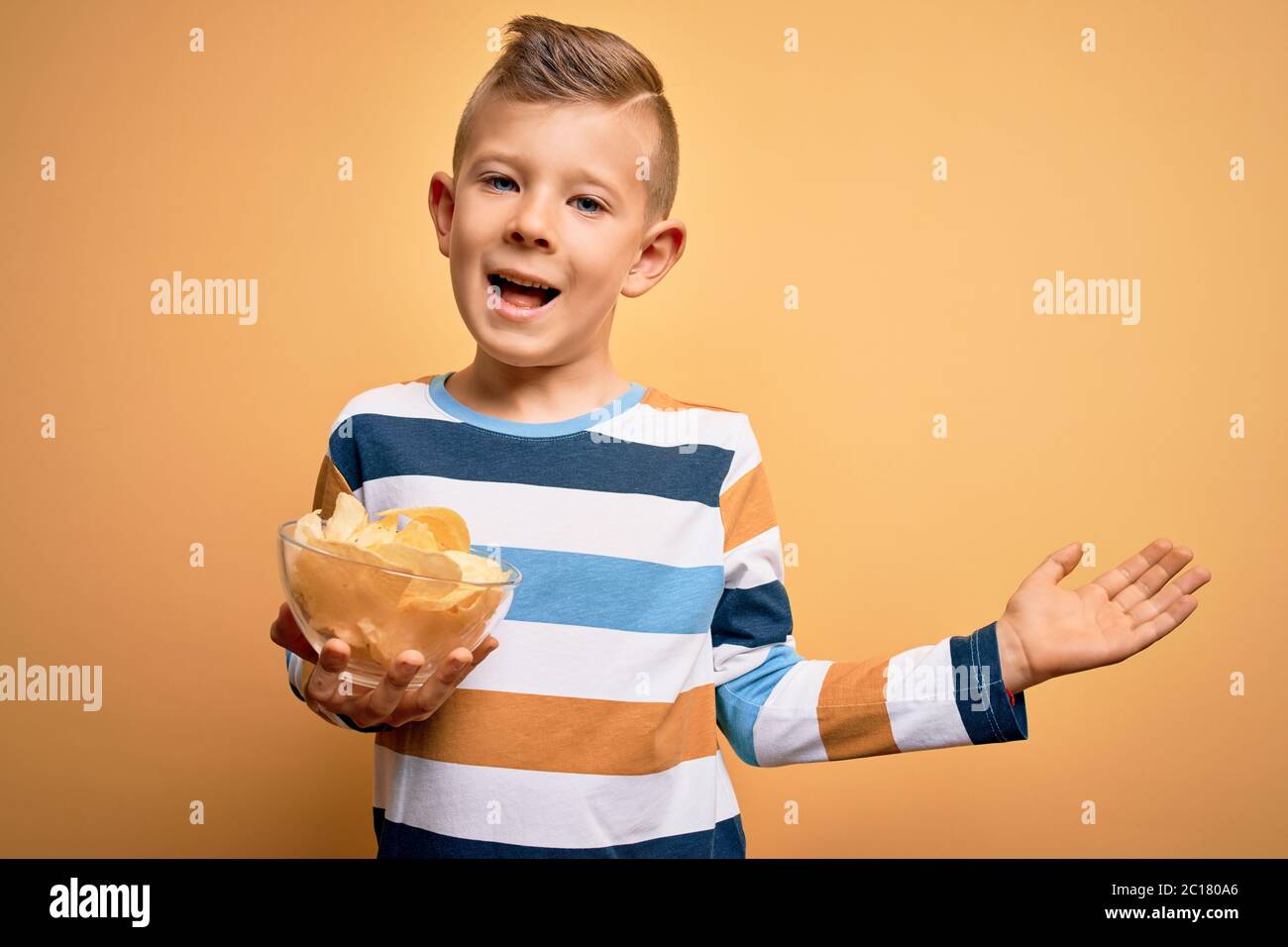 Young little caucasian kid eating unheatlhy potatoes crisps chips over ...