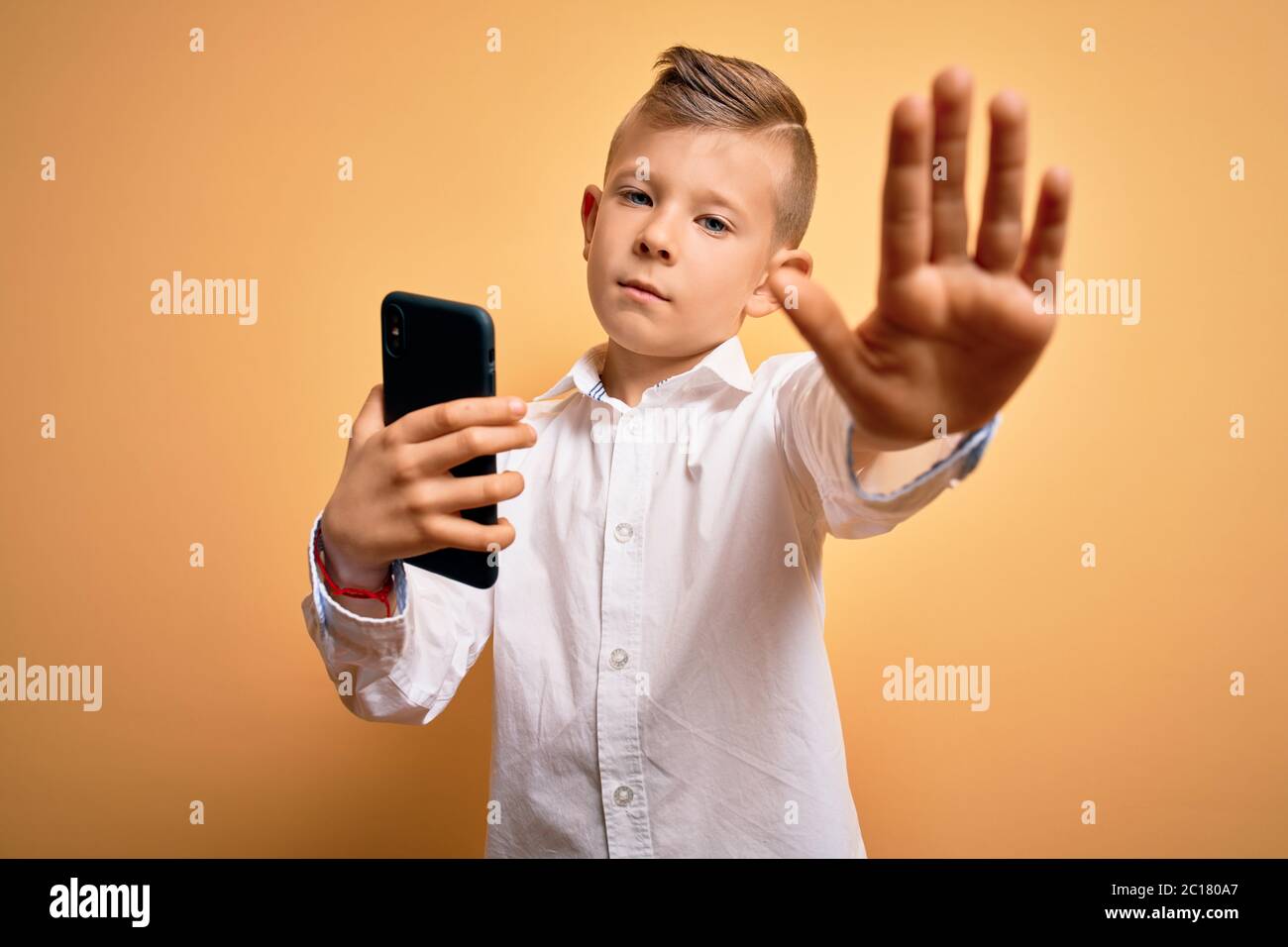 Young little caucasian kid using smartphone and looking at the screen ...