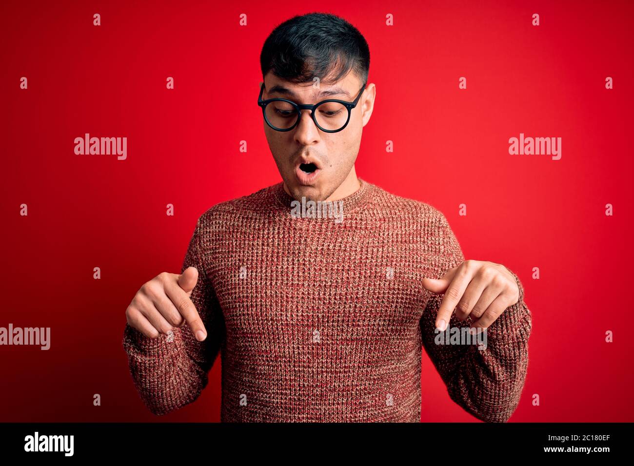 Young handsome hispanic man wearing nerd glasses over red background ...