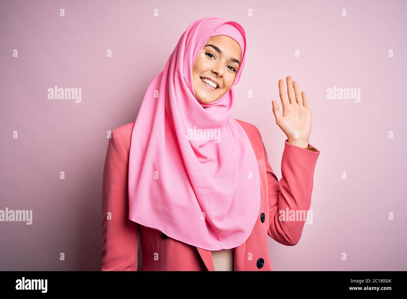 Young beautiful girl wearing muslim hijab standing over isolated pink ...