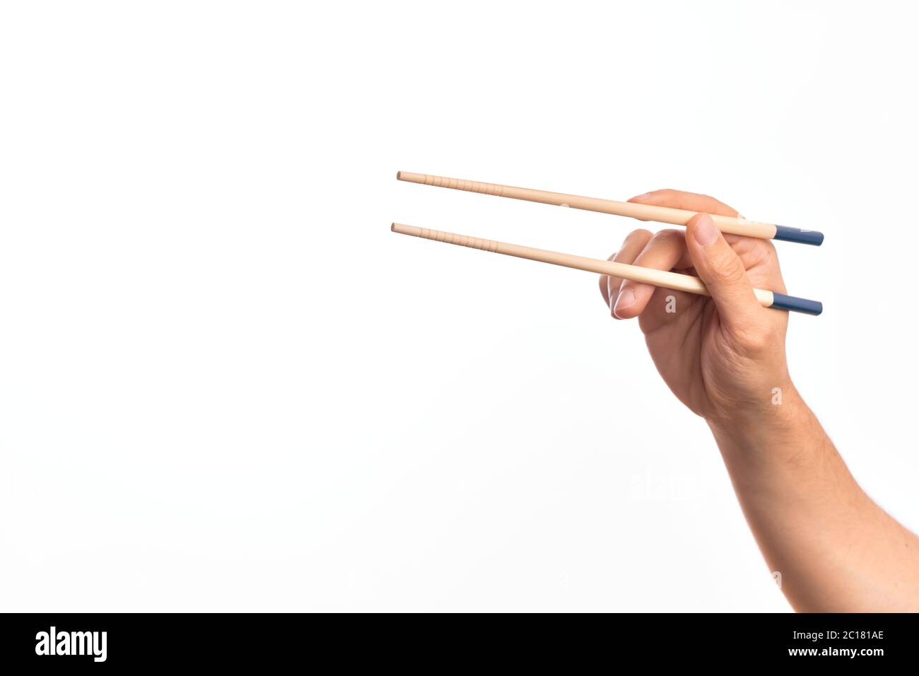 Hand of caucasian young man holding chopsticks over isolated white ...