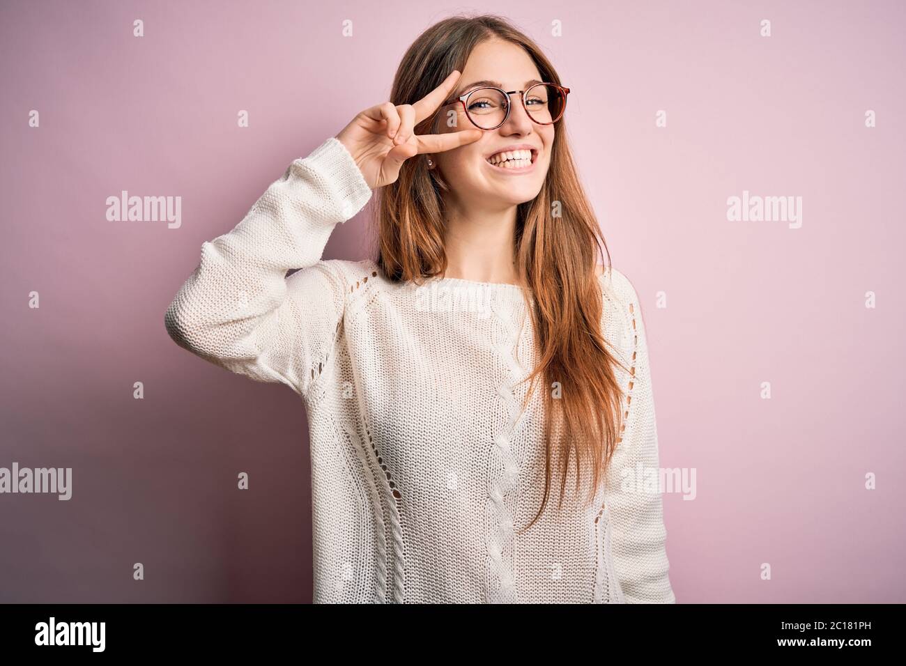 Young beautiful redhead woman wearing casual sweater and glasses over ...