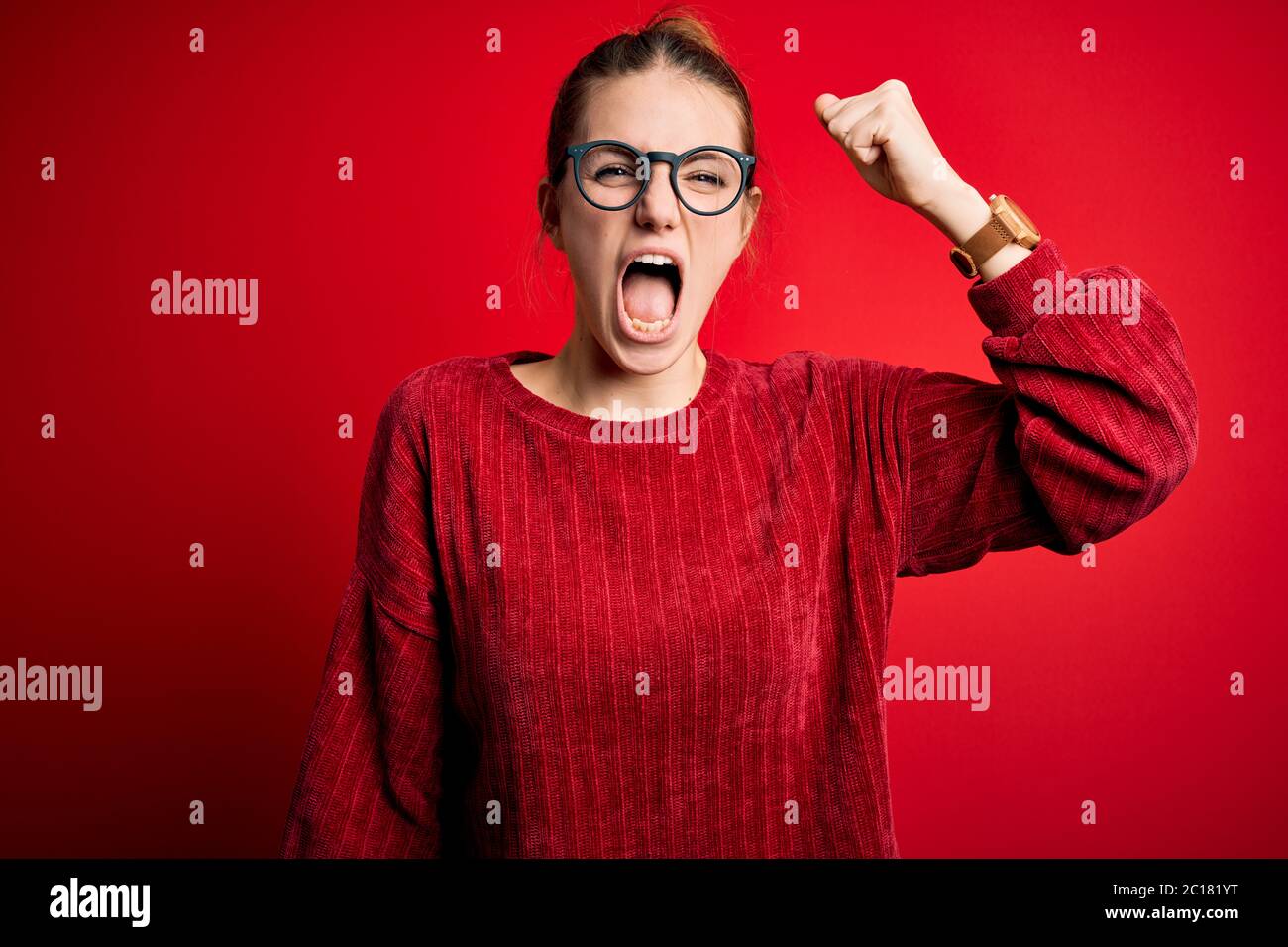 Young beautiful redhead woman wearing casual sweater over isolated red ...