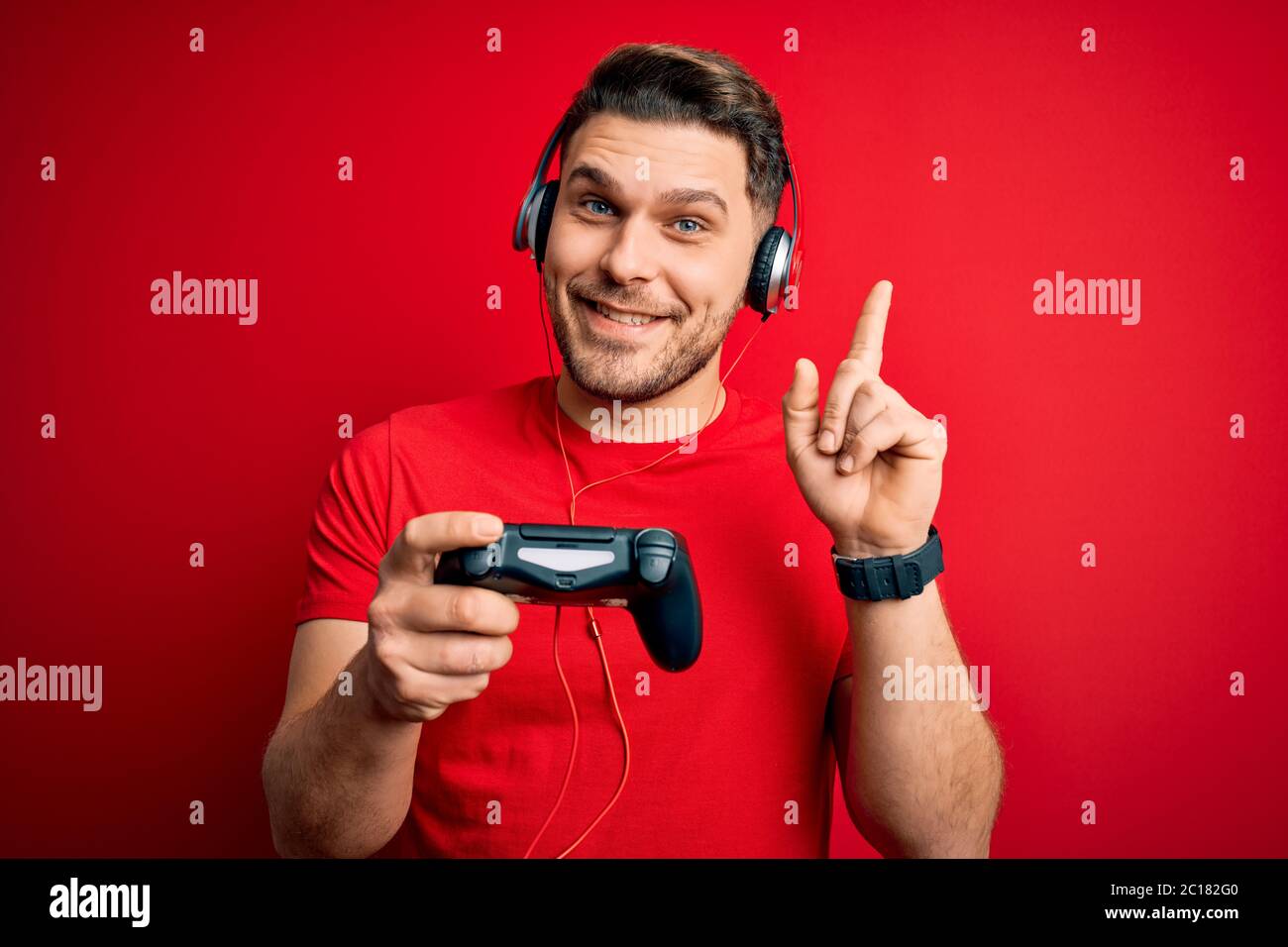 Young gamer man with blue eyes playing video games using gamepad ...