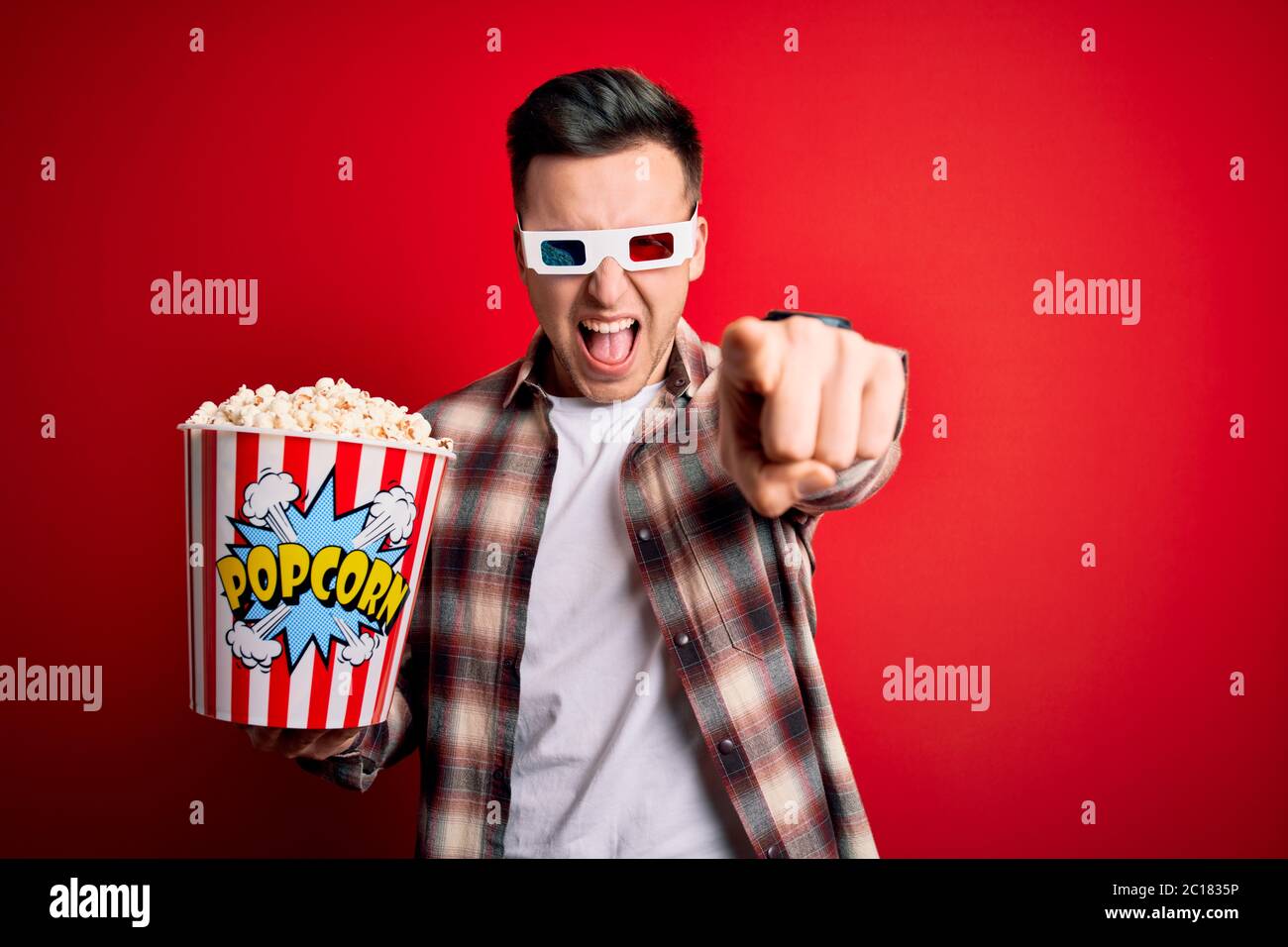 Young handsome caucasian man wearing 3d movie glasses and eating ...